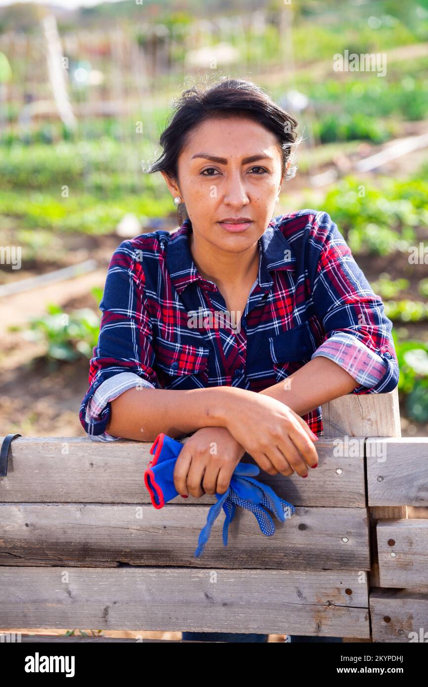 Latin American woman gardener standing near wooden fence in garden ...