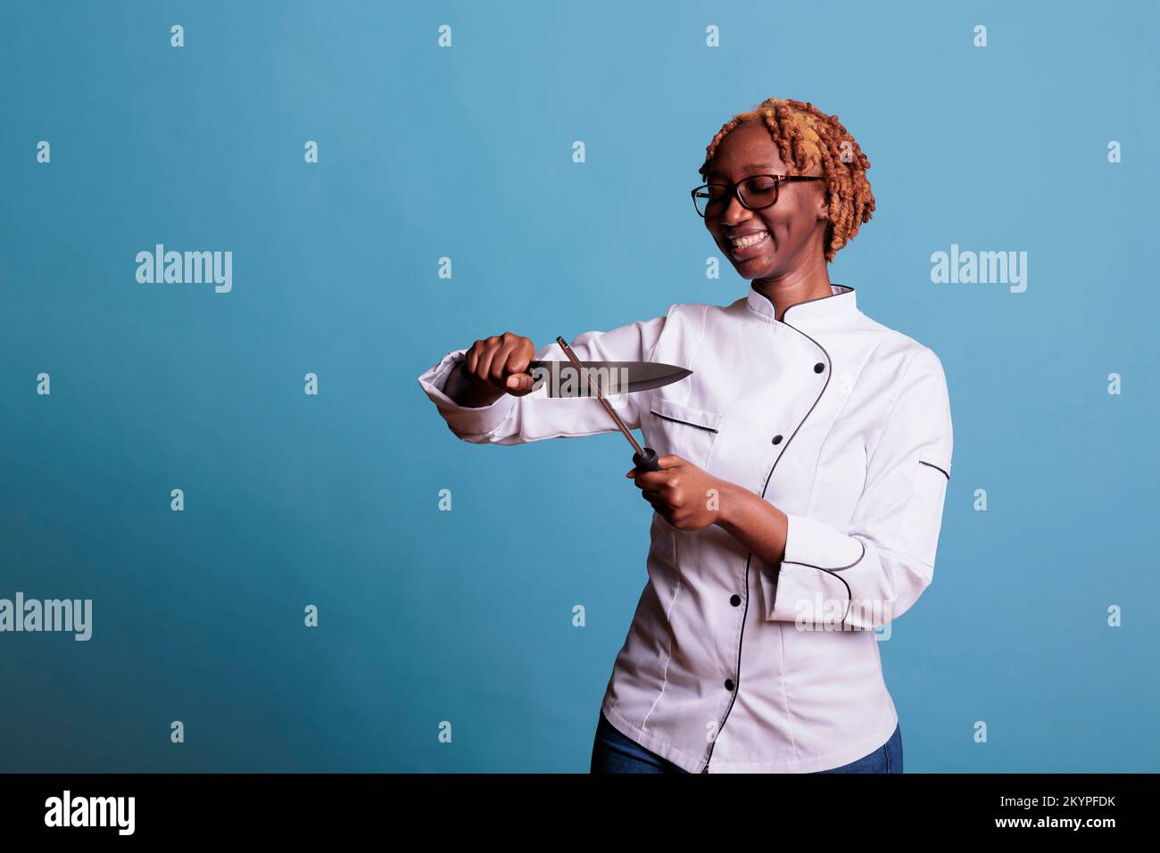 African american female chef in uniform sharpening professional knife ...