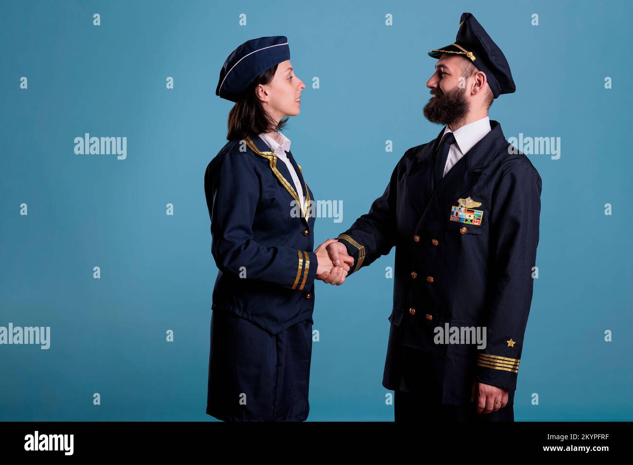 Smiling airplane pilot and flight attendant shaking hands portrait ...