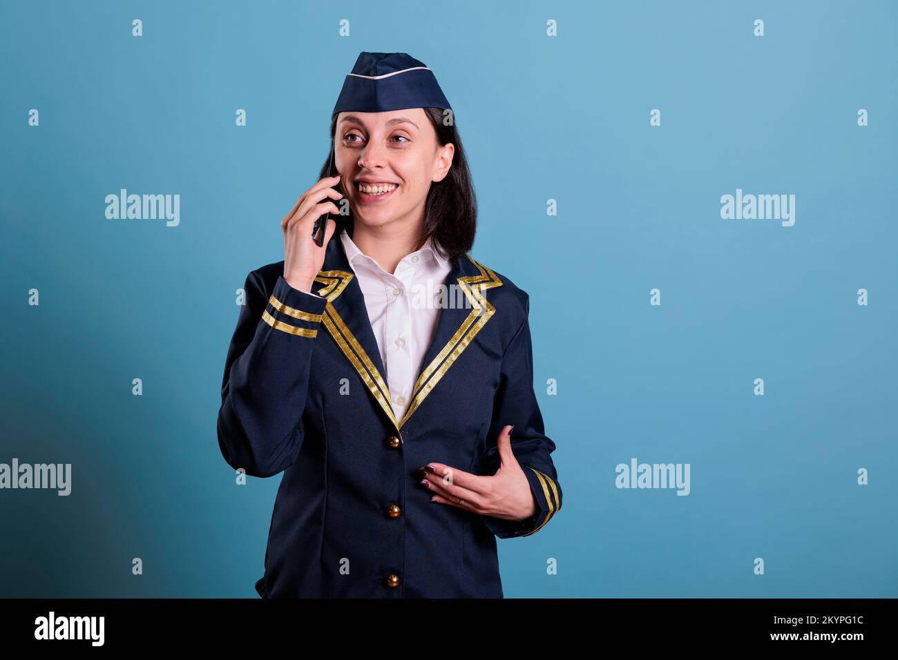 Smiling cheerful flight attendant talking on smartphone, holding mobile ...