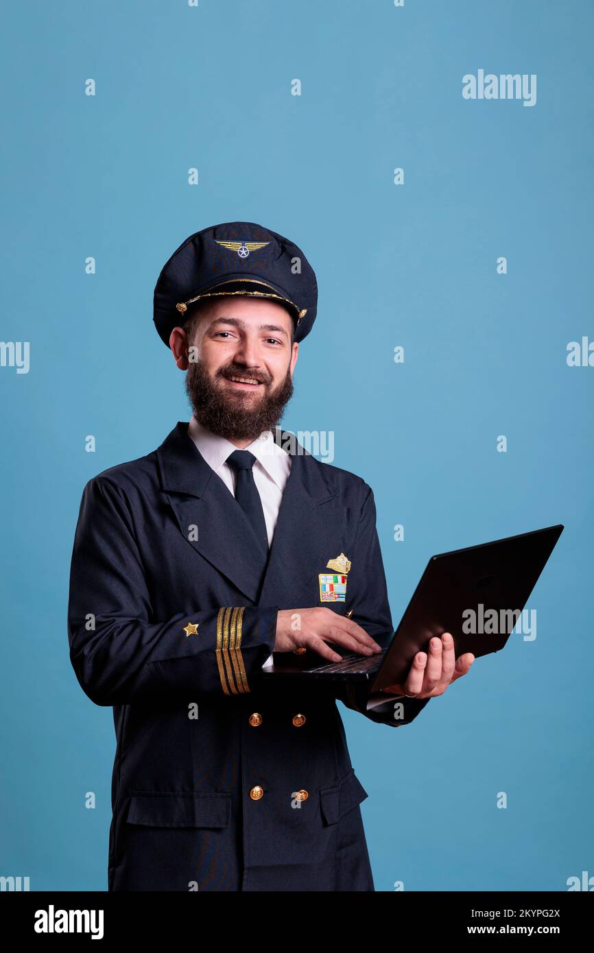 Smiling airliner pilot using laptop, typing message side view. Middle ...