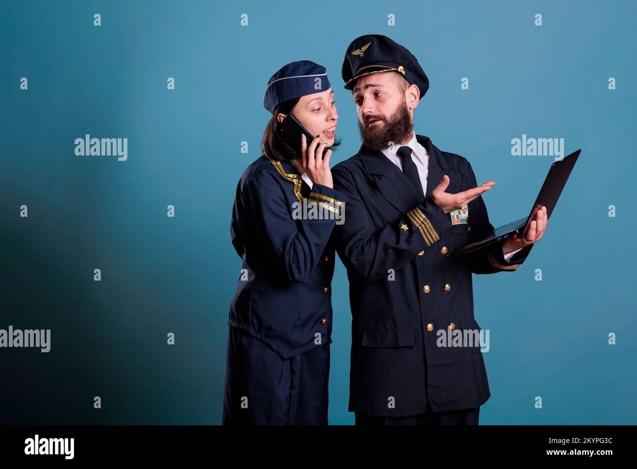 Smiling aviator using laptop while stewardess talking on smartphone ...