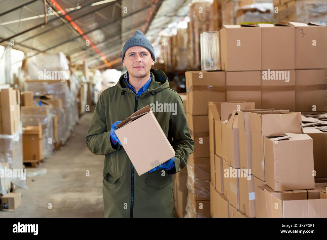 Warehouse worker carrying large box of goods in arehouse Stock Photo ...