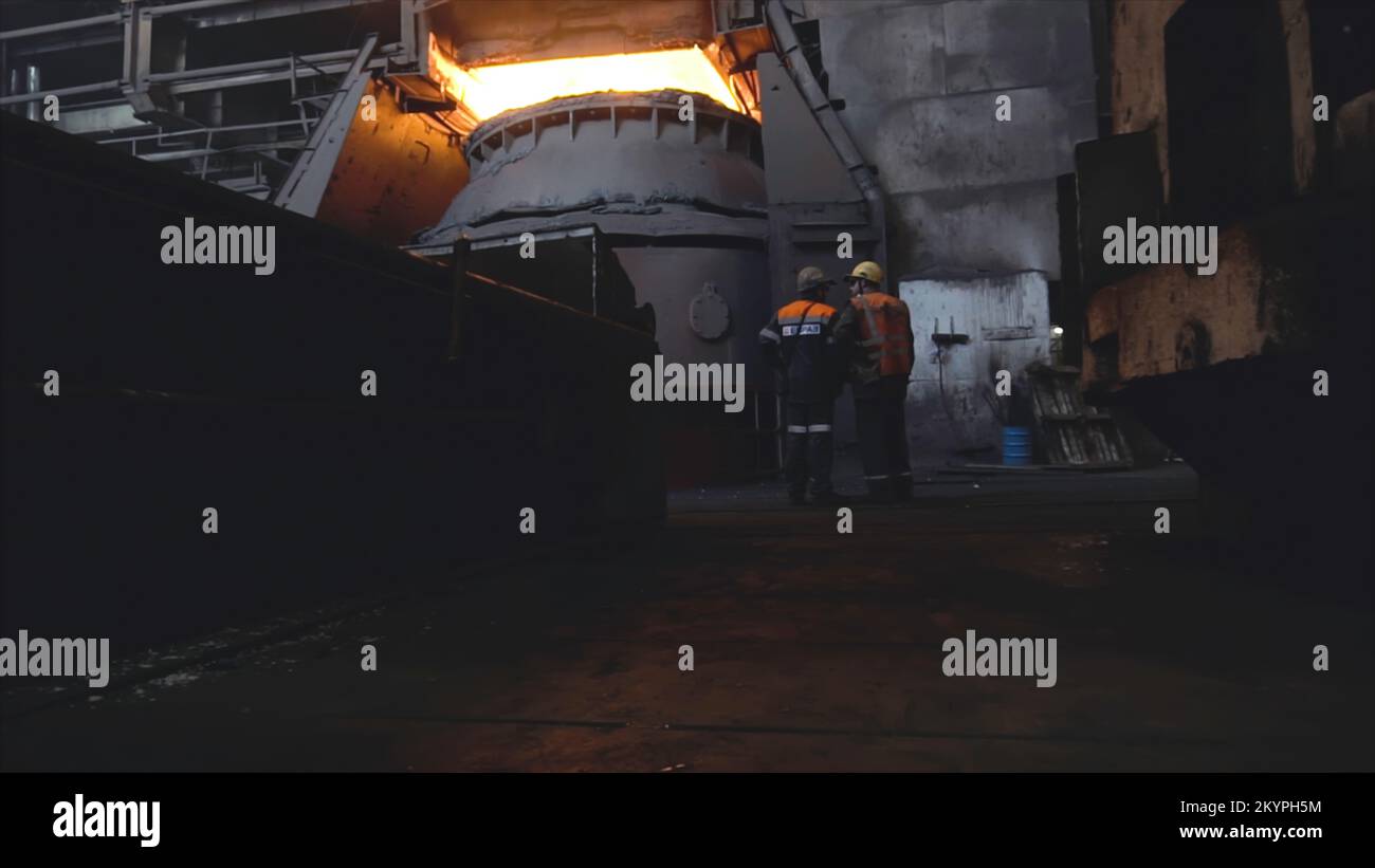 View of two workers from back in uniform and helmets on background of ...
