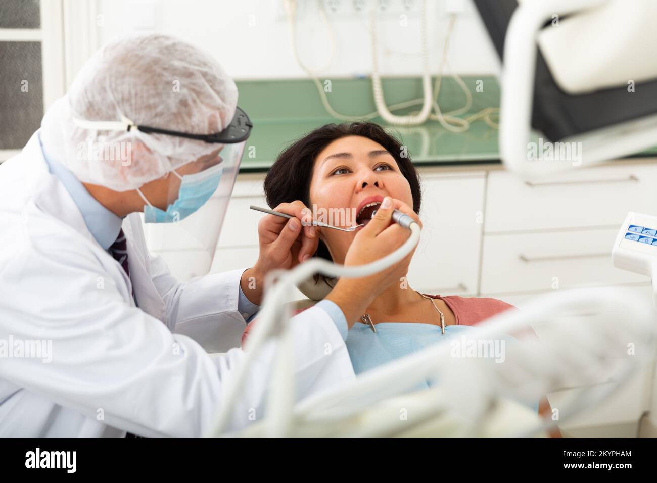 Dentist filling teeth for woman patient sitting in medical chair Stock ...