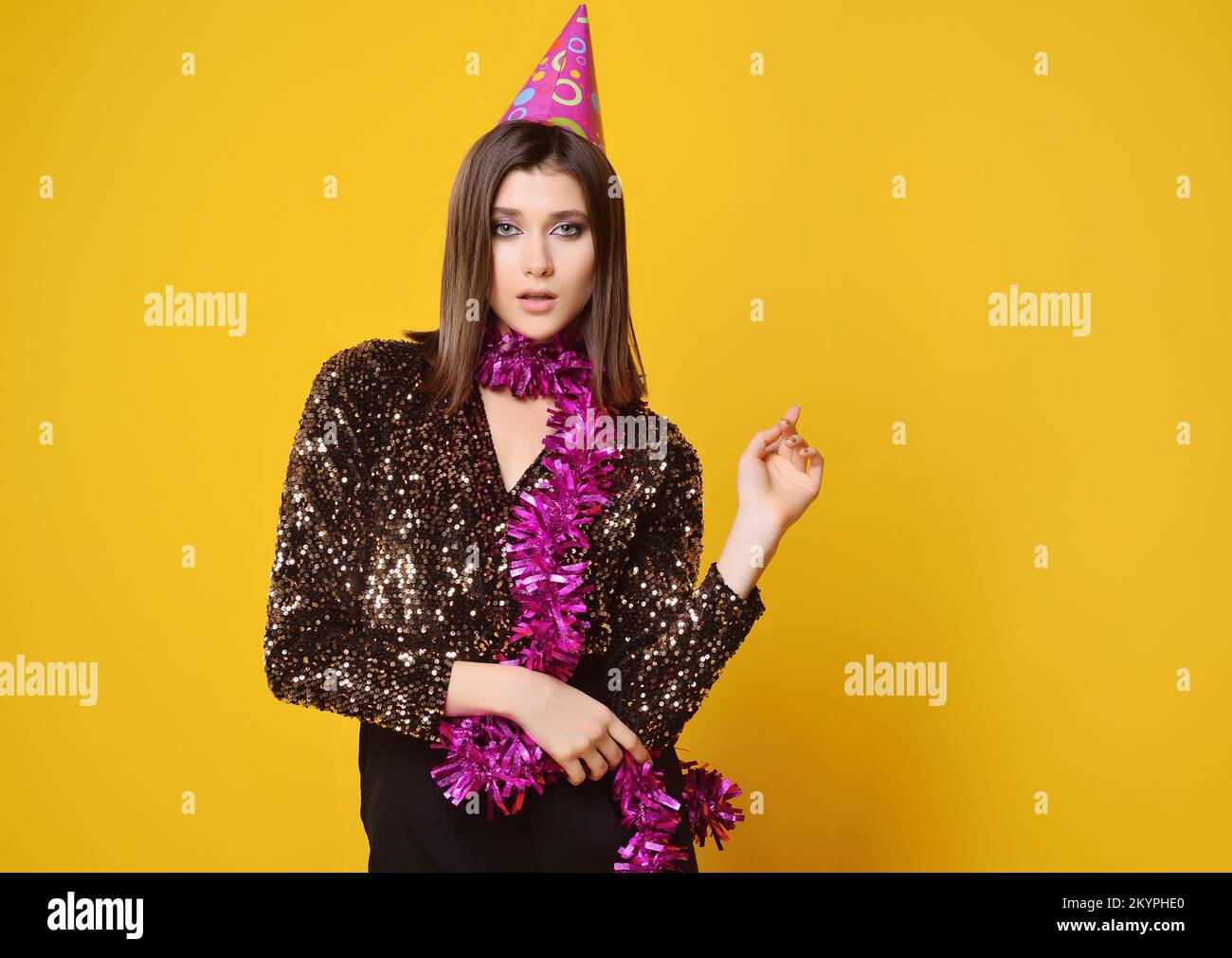 pretty woman in golden dress wearing pink boa and party cap on yellow ...