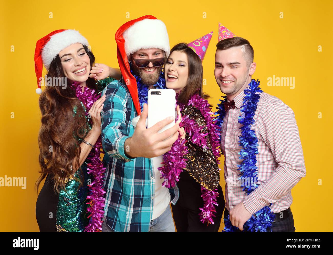 group or company of friends in santa hat, party hats, boas celebrating ...