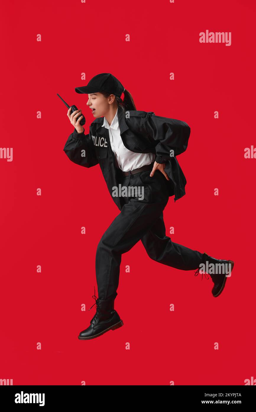 Female police officer with radio transmitter jumping on red background ...