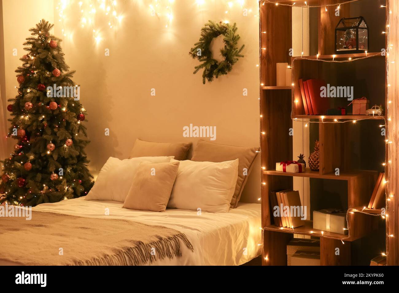 Interior of bedroom with Christmas tree, shelving unit and glowing ...