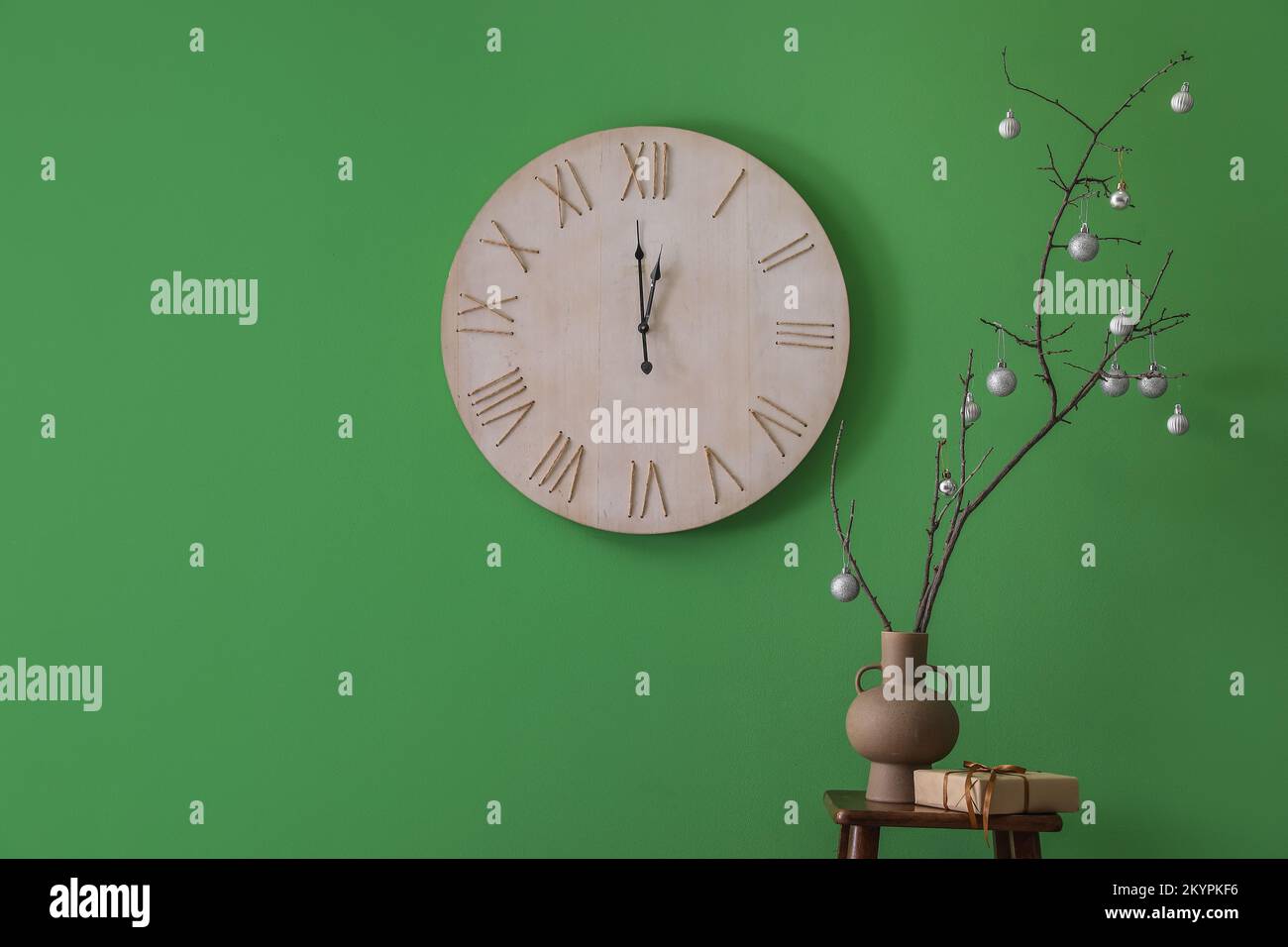 Vase with tree branches, Christmas balls and gift on table near green ...