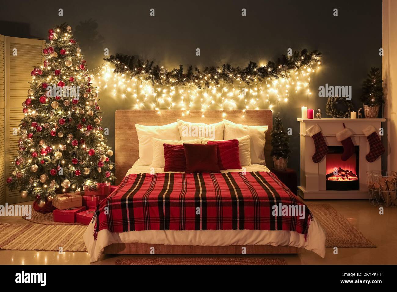 Interior of bedroom with Christmas tree, fireplace and glowing lights ...