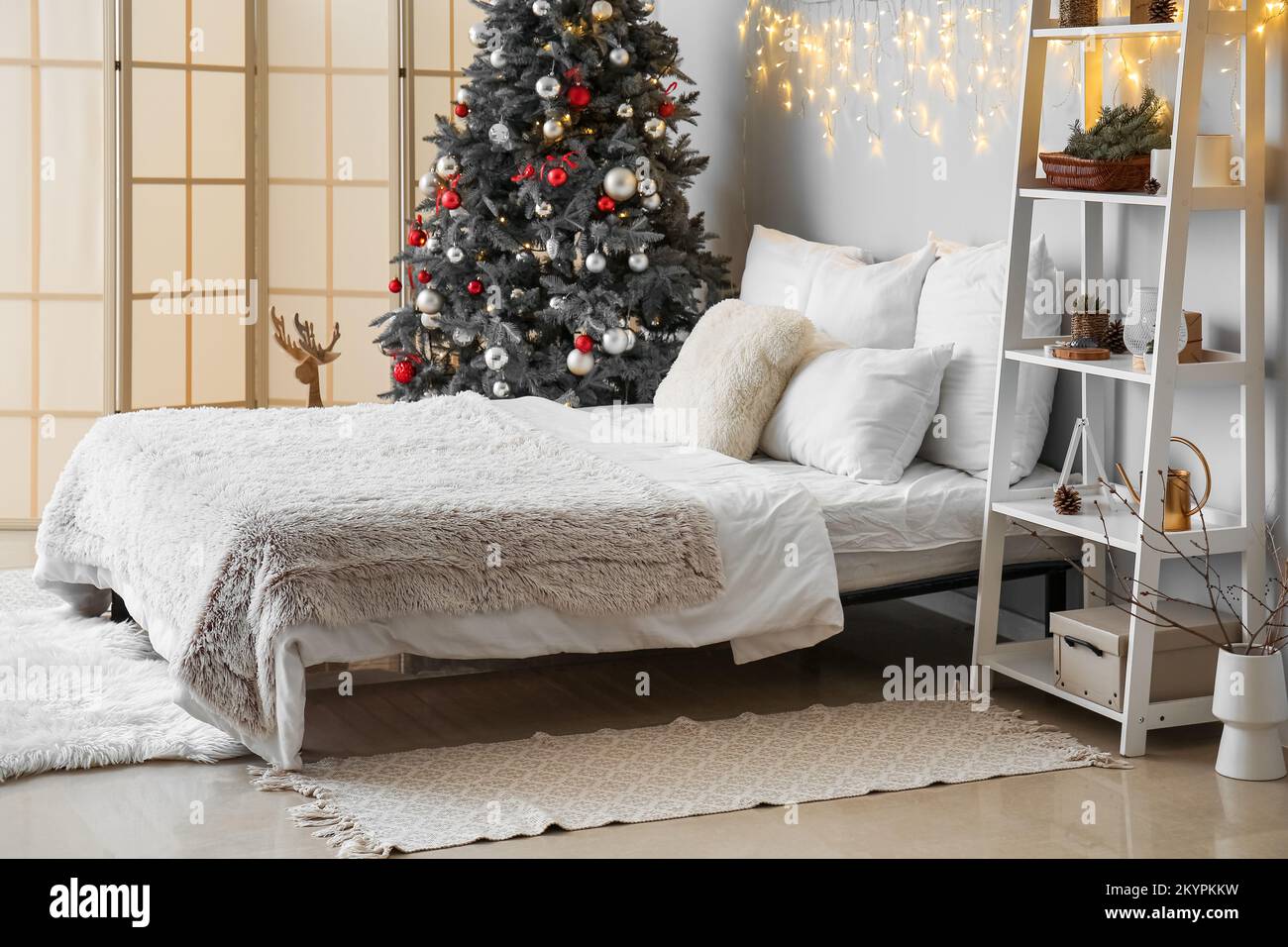 Interior of bedroom with Christmas tree, glowing lights and shelving ...