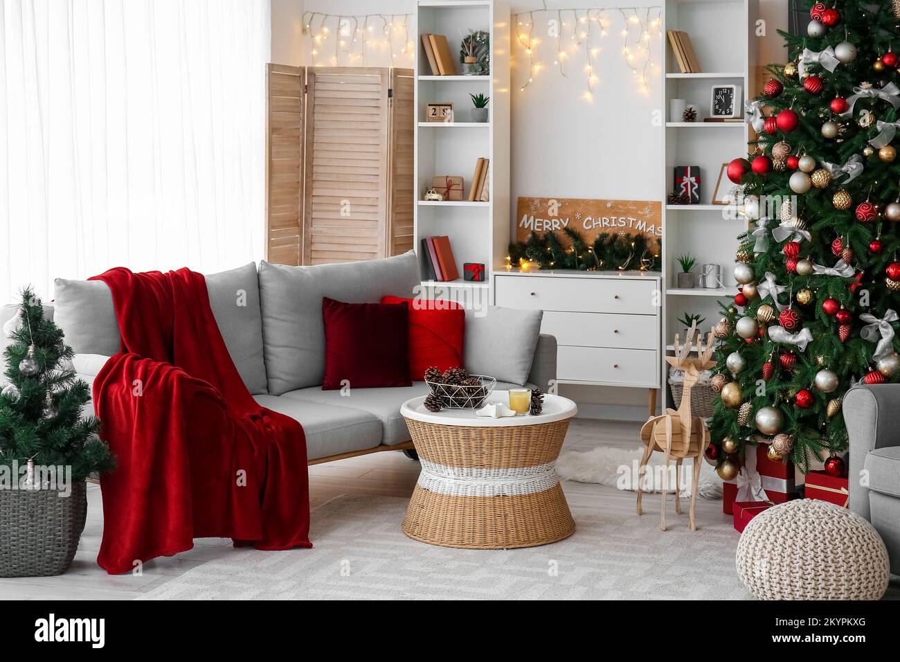 Interior of living room with Christmas trees, sofa and glowing lights ...