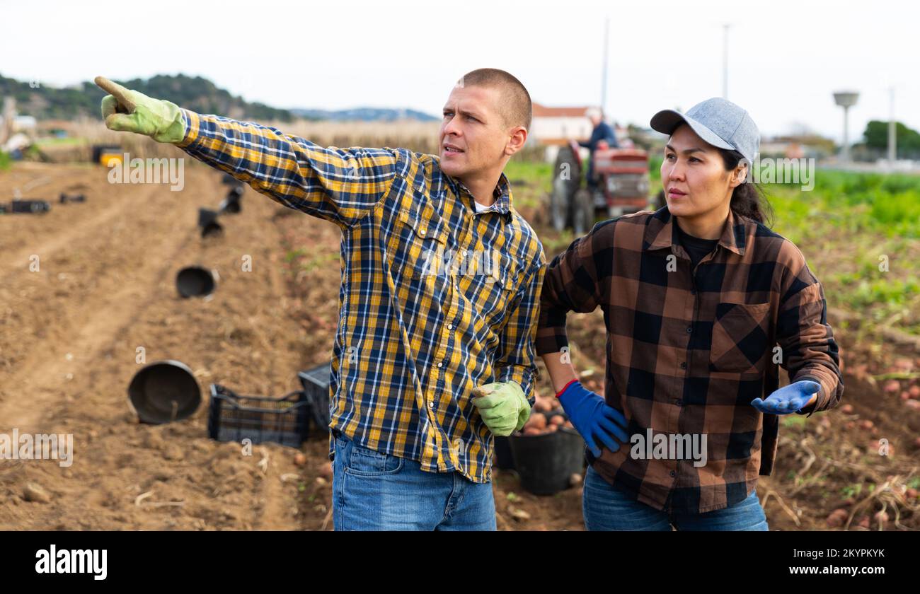 Two farm workers on a farm field pointing to something Stock Photo - Alamy
