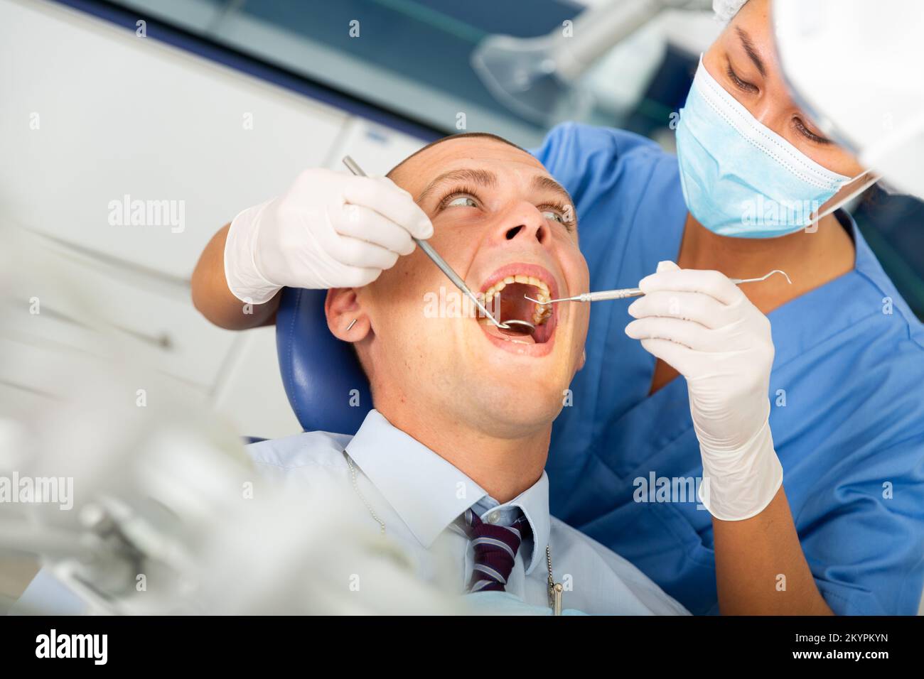 Dentist inspects male patient teeth Stock Photo - Alamy