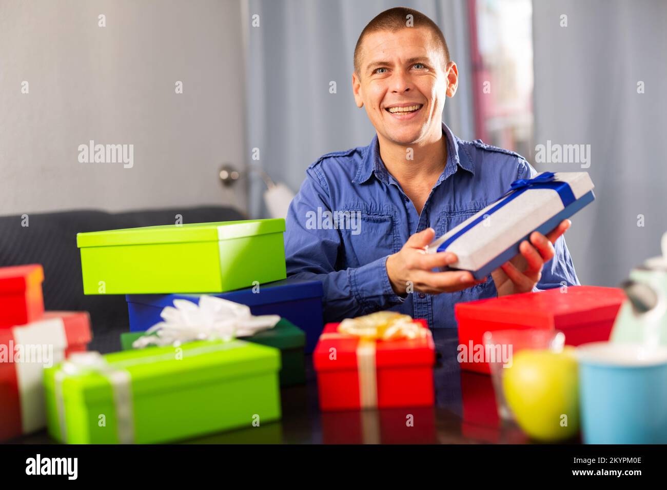 Man sitting with many presents in colorful boxes Stock Photo - Alamy