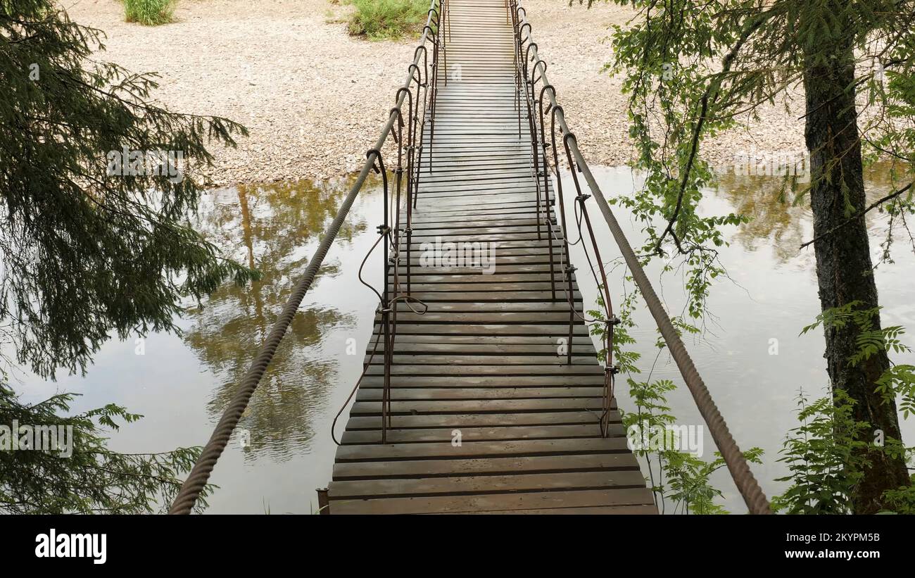 Wooden bridge suspended over forest river. Stock footage. Old hanging ...