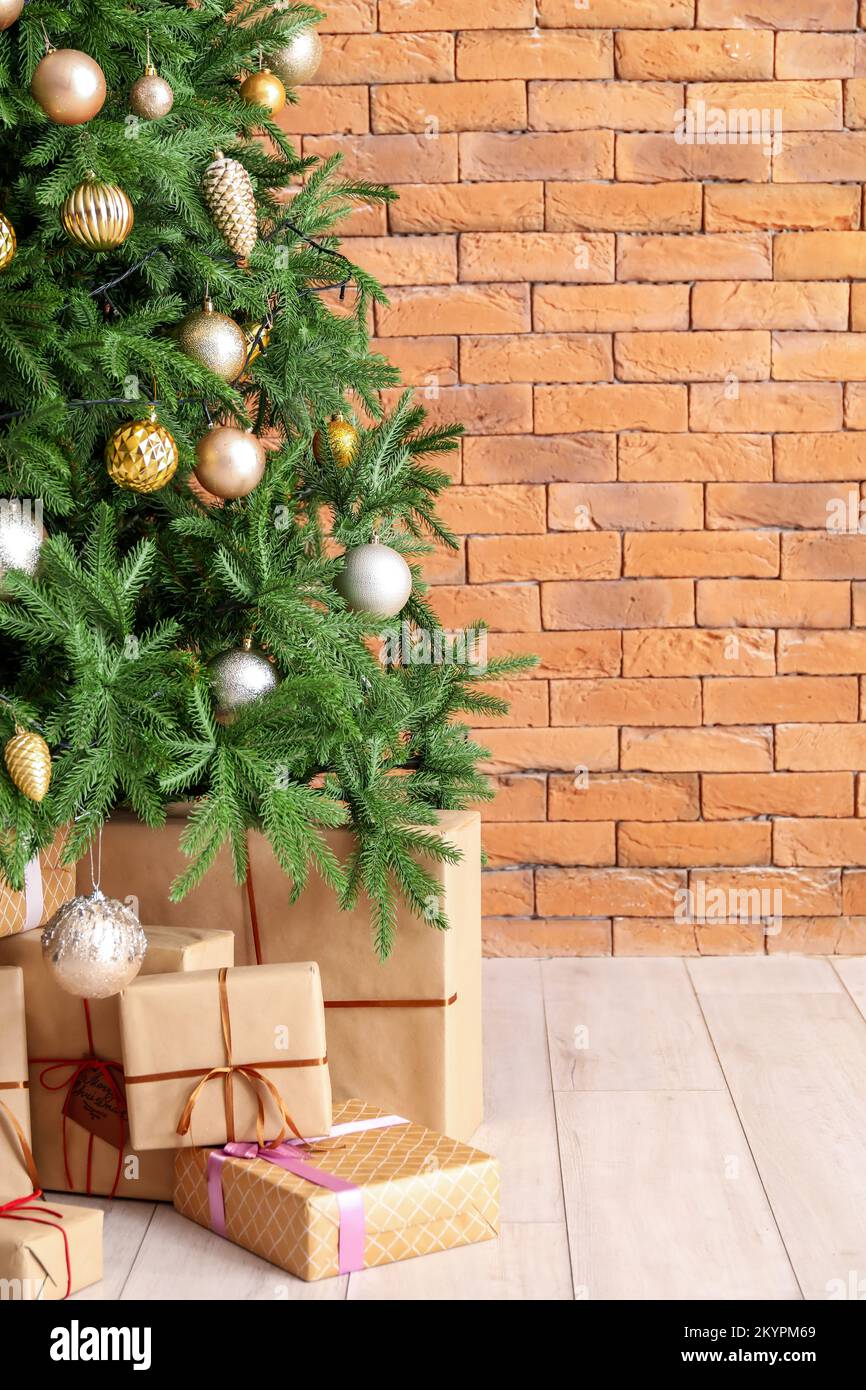 Decorated Christmas tree with presents near brick wall Stock Photo - Alamy