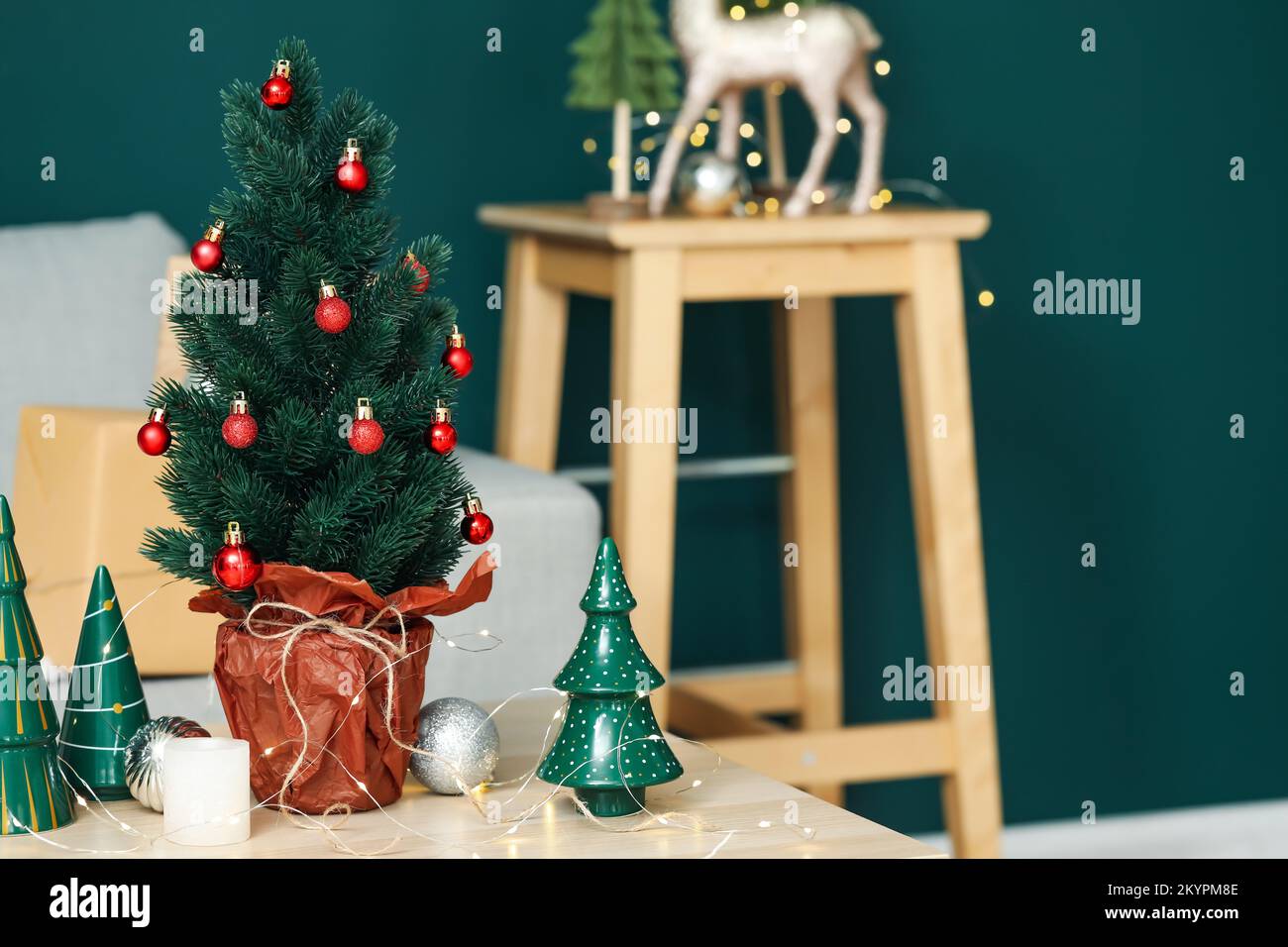 Small Christmas tree with toys, candle and glowing lights on table in ...