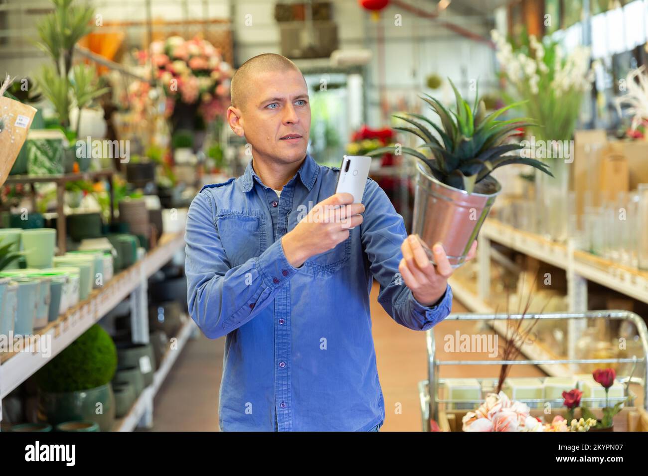 Man taking pictures of replica plants while shopping in store Stock ...