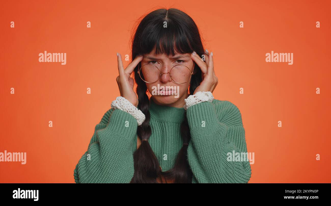 Hipster young adult woman in sweater rubbing temples to cure headache ...