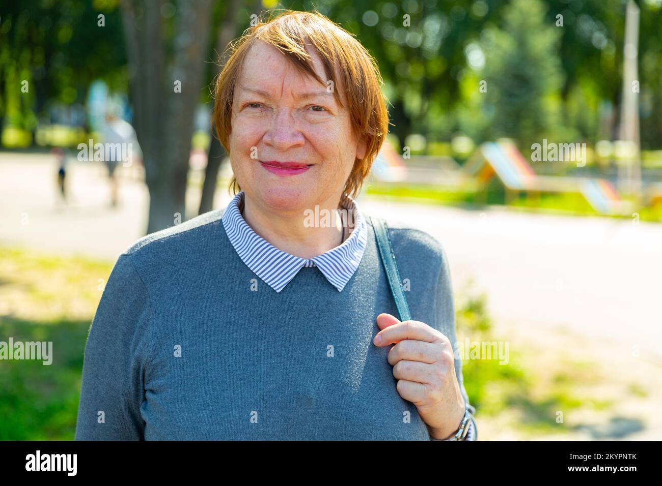 Smiling mature lady in urban park Stock Photo - Alamy
