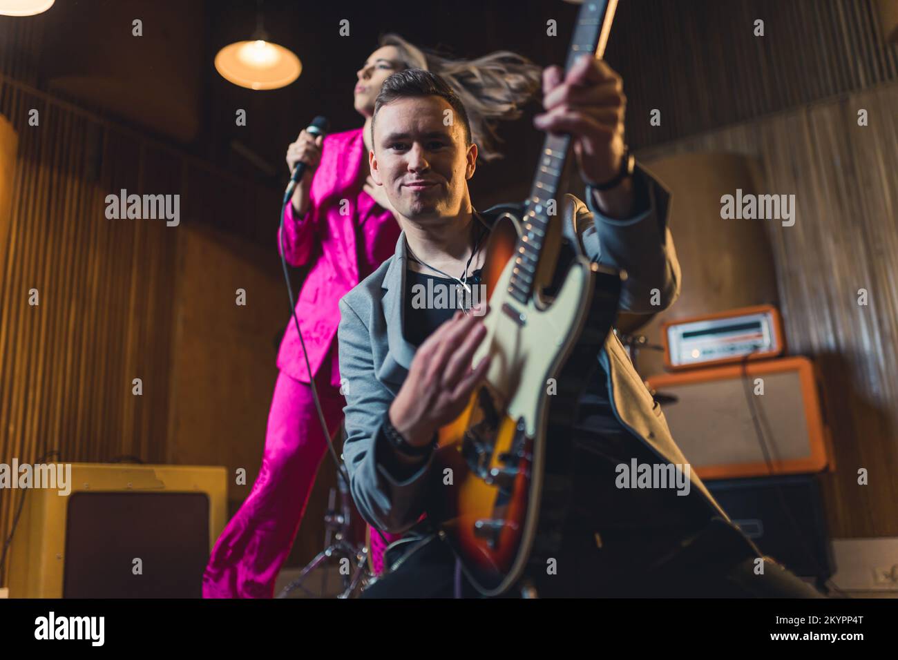 Mid adult male guitarist holding electric guitar, kneeling in front of ...