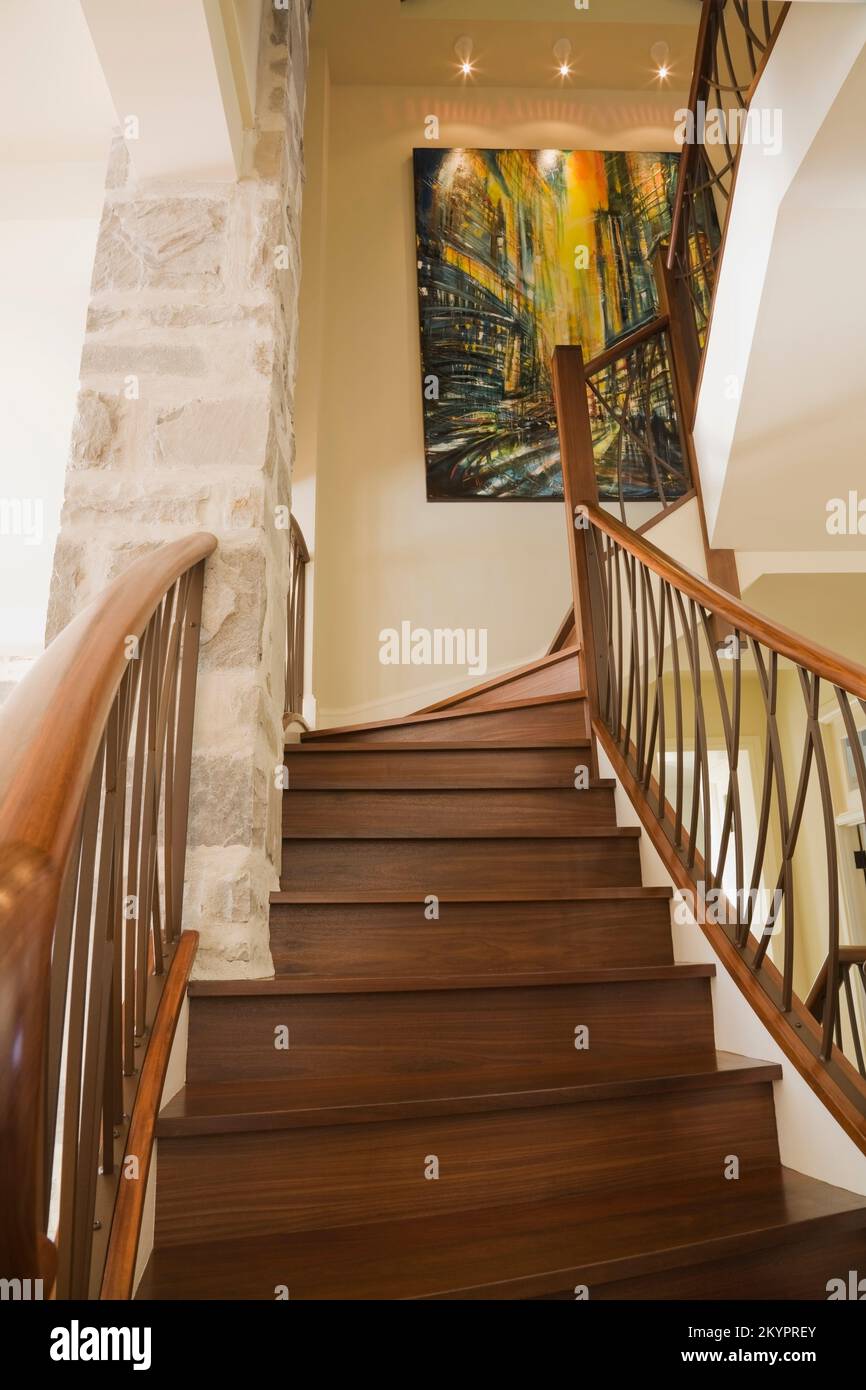 Ornate wooden staircase and abstract painting on wall inside luxurious ...