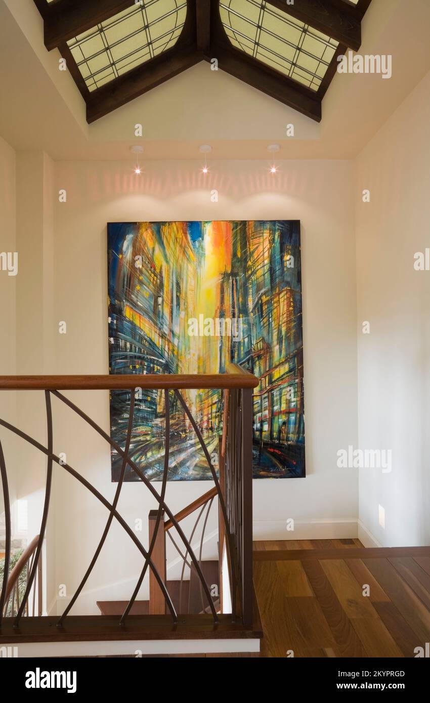 Skylight above ornate wooden staircase and abstract painting on wall ...