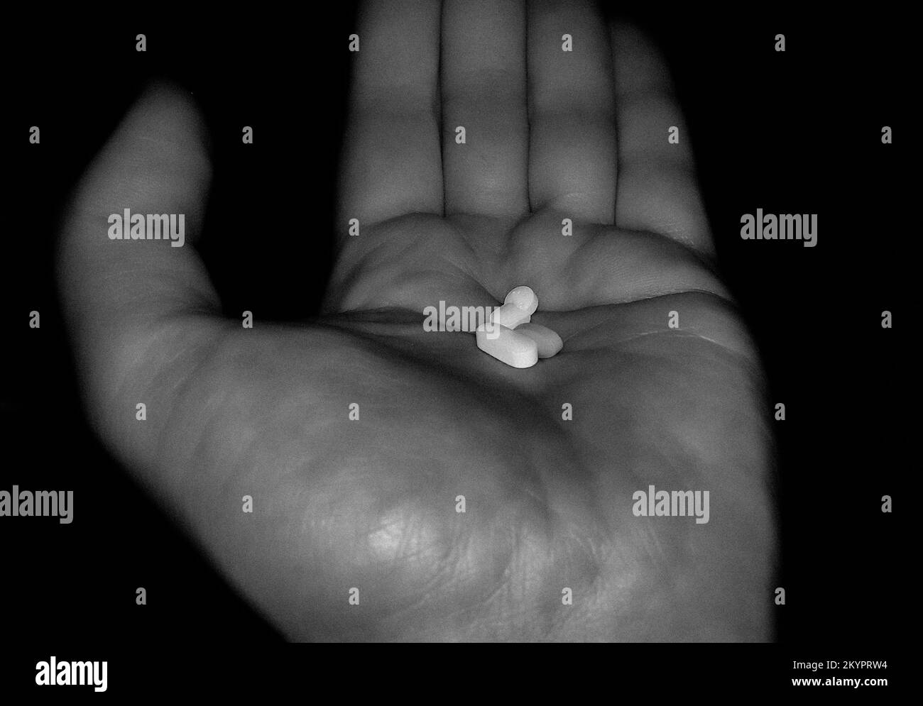 Cropped hand holding medicine against black background Stock Photo - Alamy