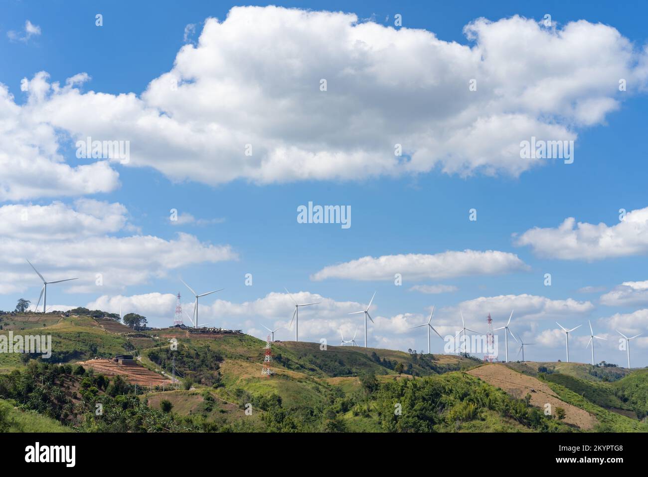 The wind turbines in the top of the grass hill underneath the group of ...