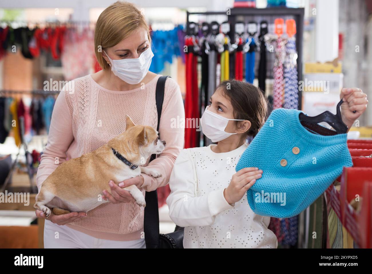 Woman in mask in pet store during shopping with her daughter with dog ...