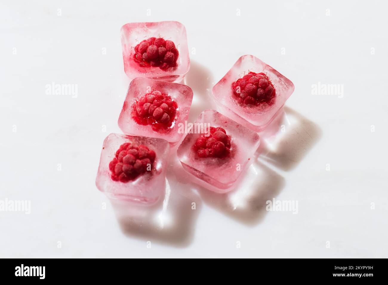 Frozen Raspberry in Ice Cube, Close-up in White Marble Surface Stock ...