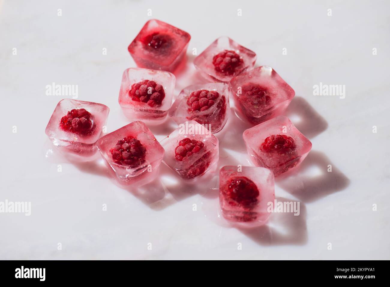 Frozen Raspberry in Ice Cube, Close-up in White Marble Surface Stock ...