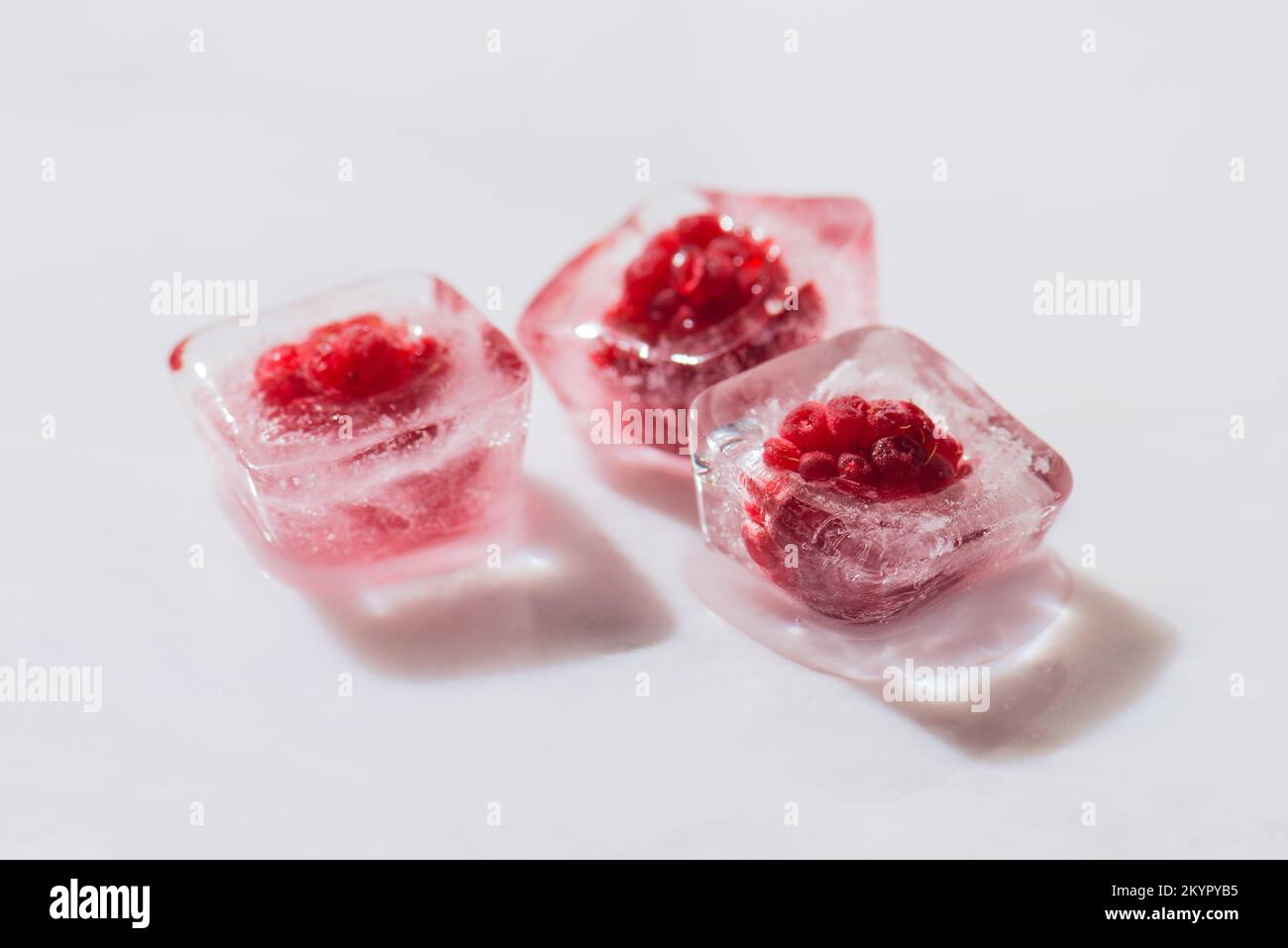 Frozen Raspberry in Ice Cube, Close-up in White Marble Surface Stock ...