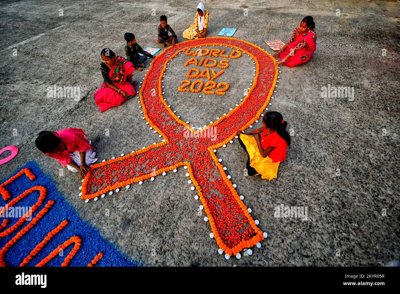 A group of activists seen lighting candles around a red ribbon during ...