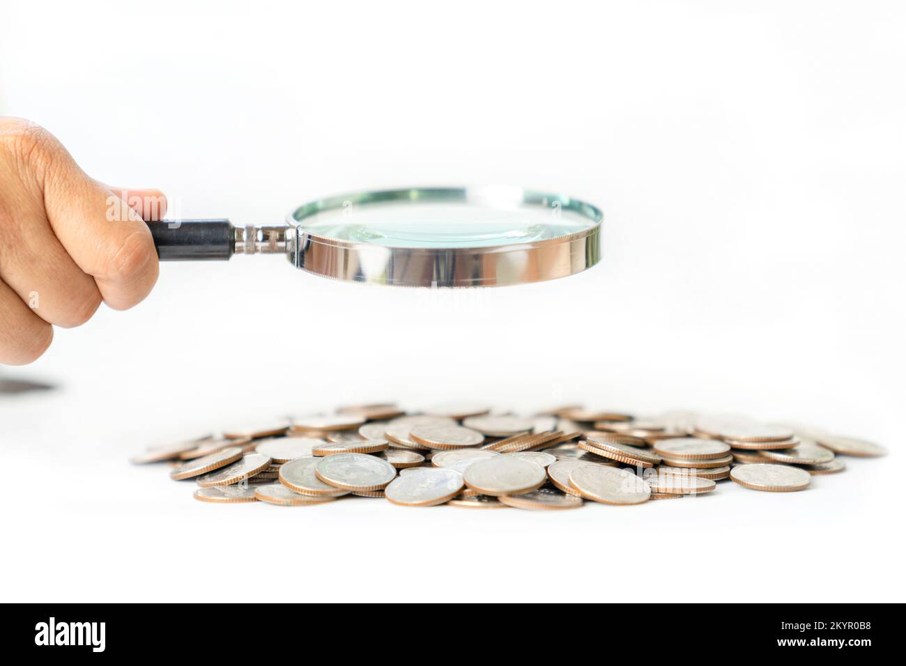 Hand of magnify glass focus a pile of money on isolate white background ...