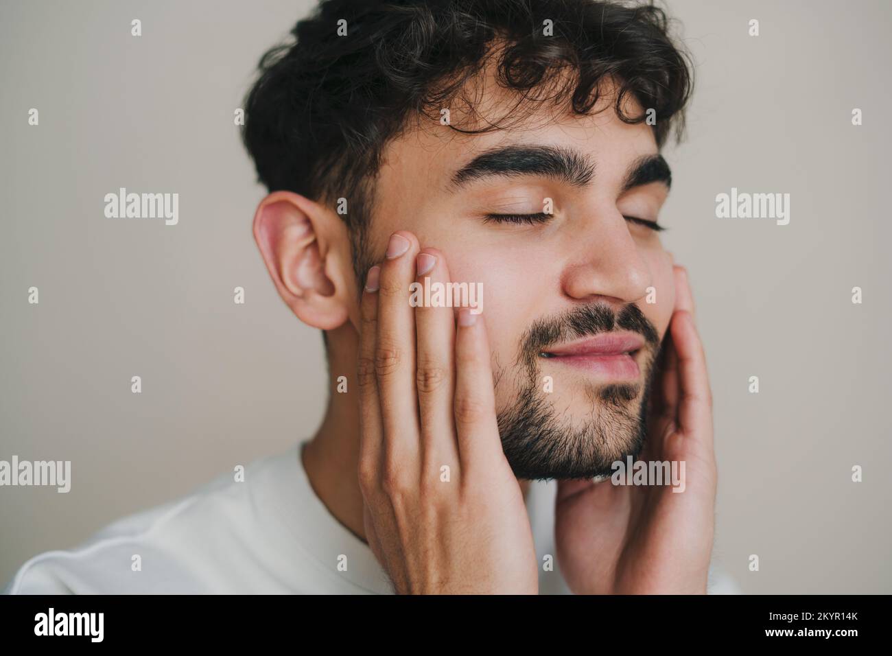 Close-up portrait of a handsome man touching face with fingers, feeling ...