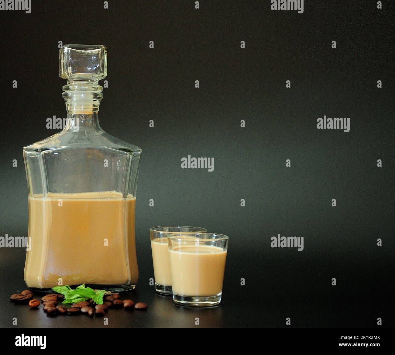 A bottle of coffee cream liqueur on a black background, next to roasted ...