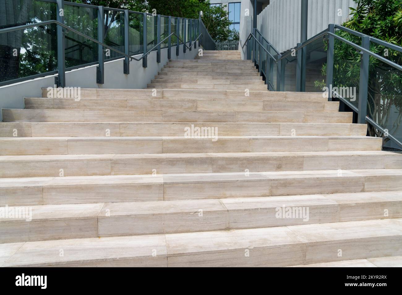 Wide outdoor stairs with glass baluster and metal bar handrails at ...