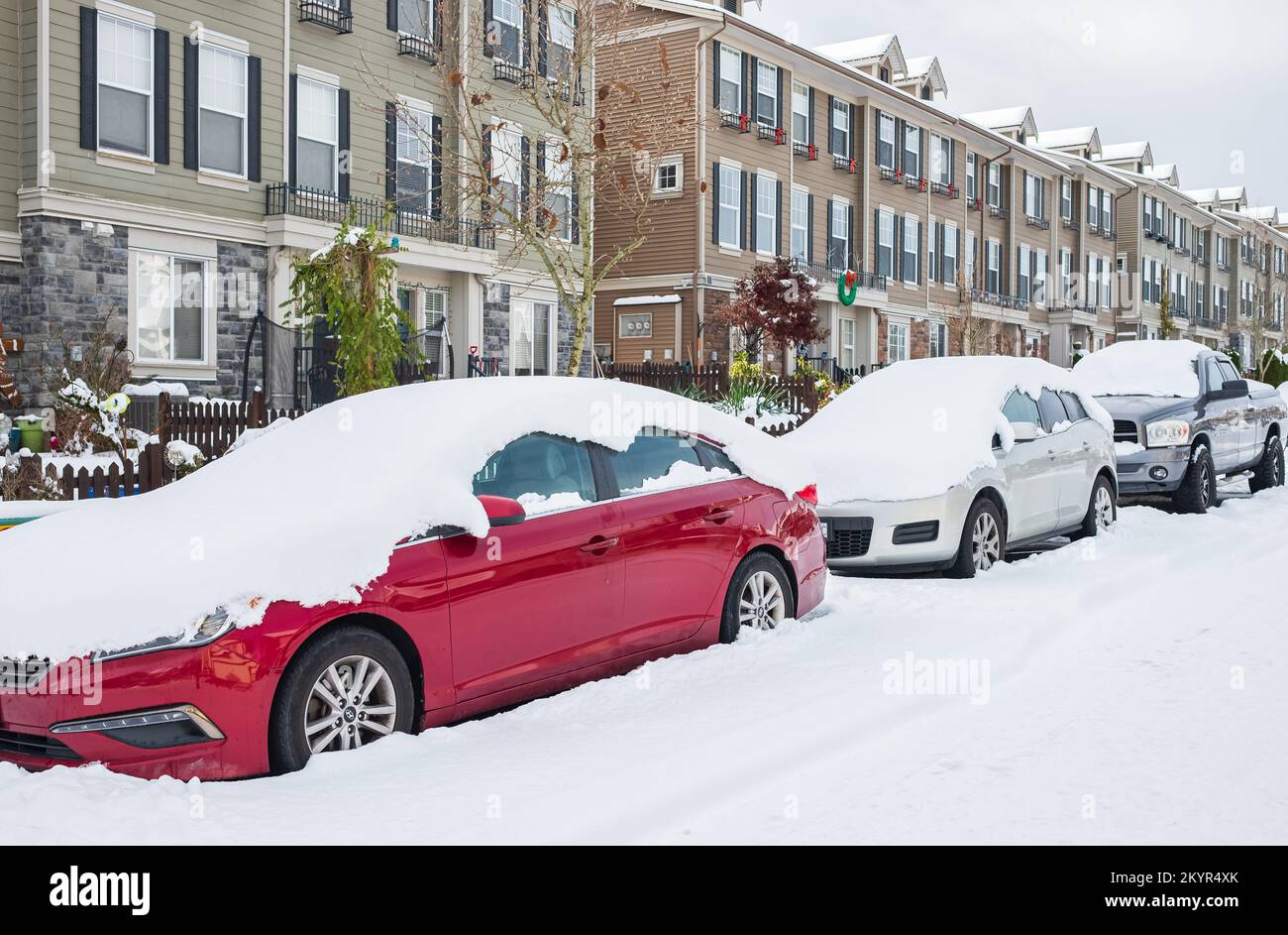 Car under snow in winter. Parked cars and the road are covered with ...