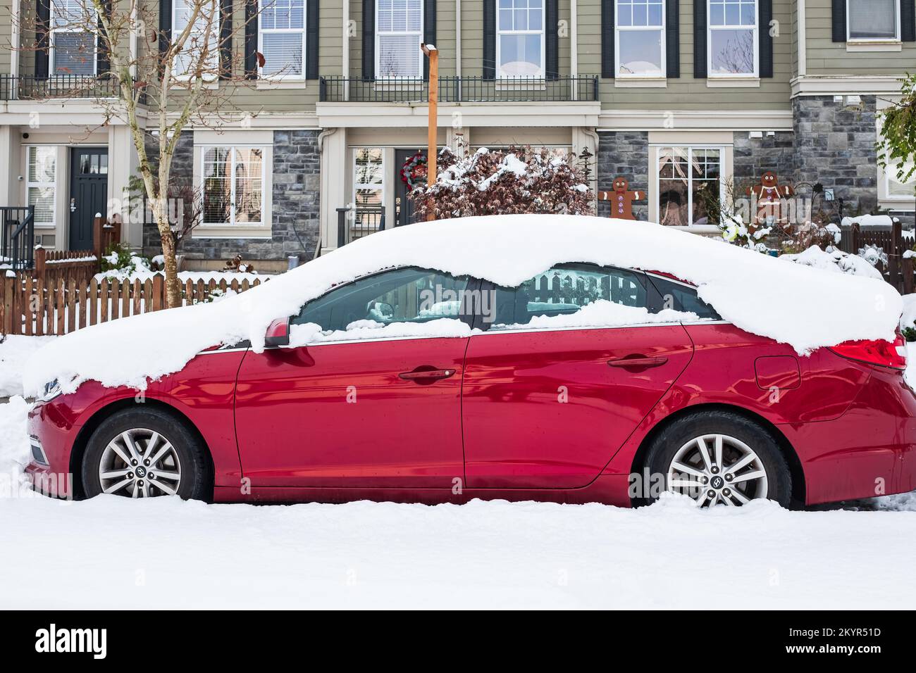 Car under snow in winter. Parked cars and the road are covered with ...