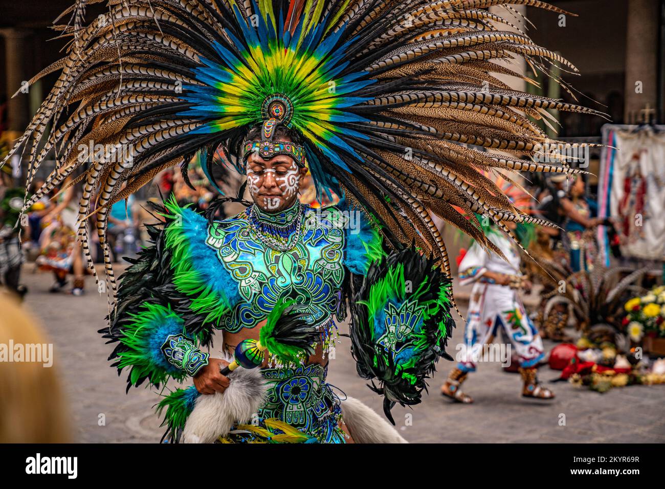 Indigenous man wearing a vibrant green and blue head dress at the Danza ...