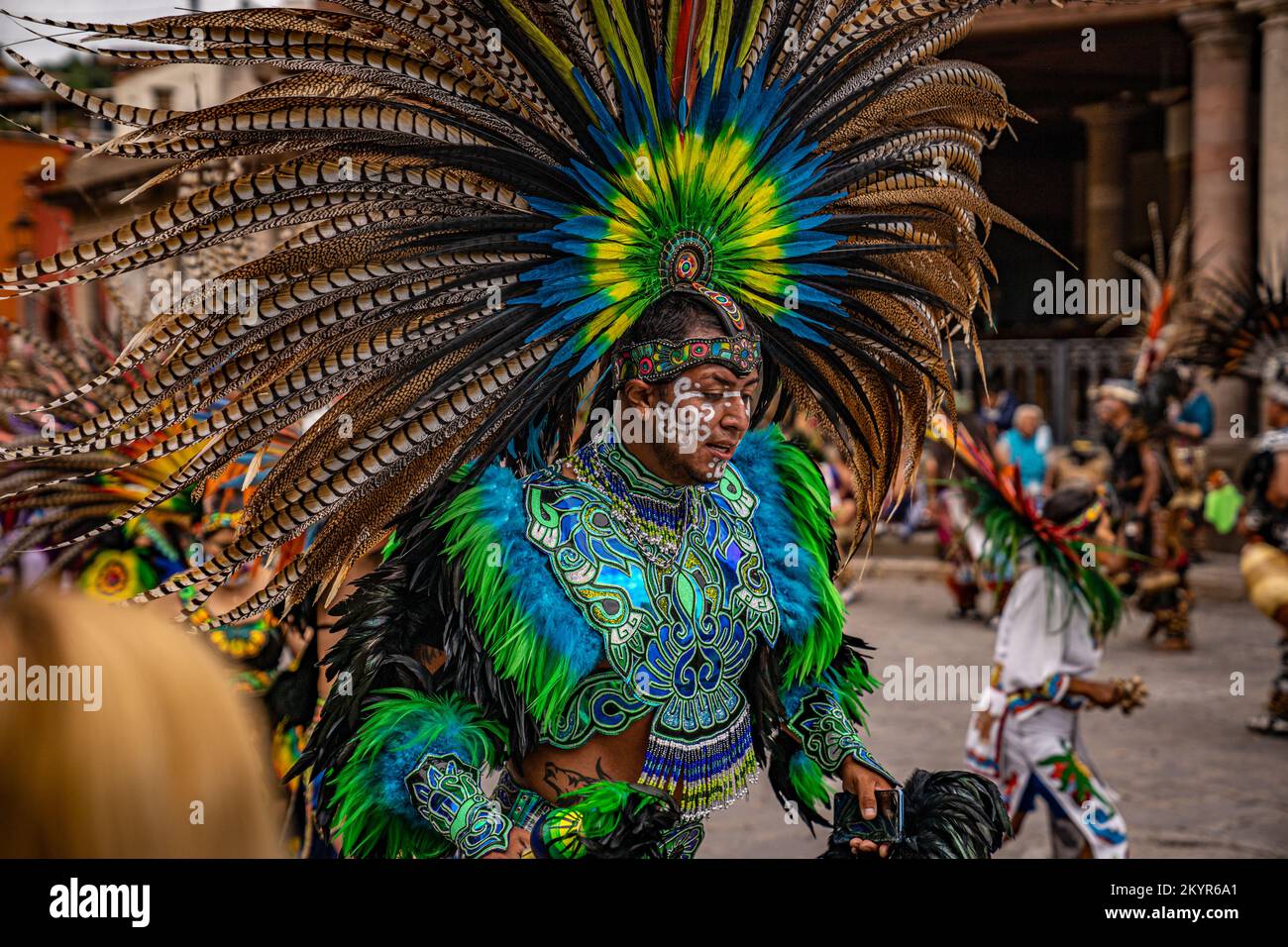 Indigenous man wearing a vibrant green and blue head dress at the Danza ...