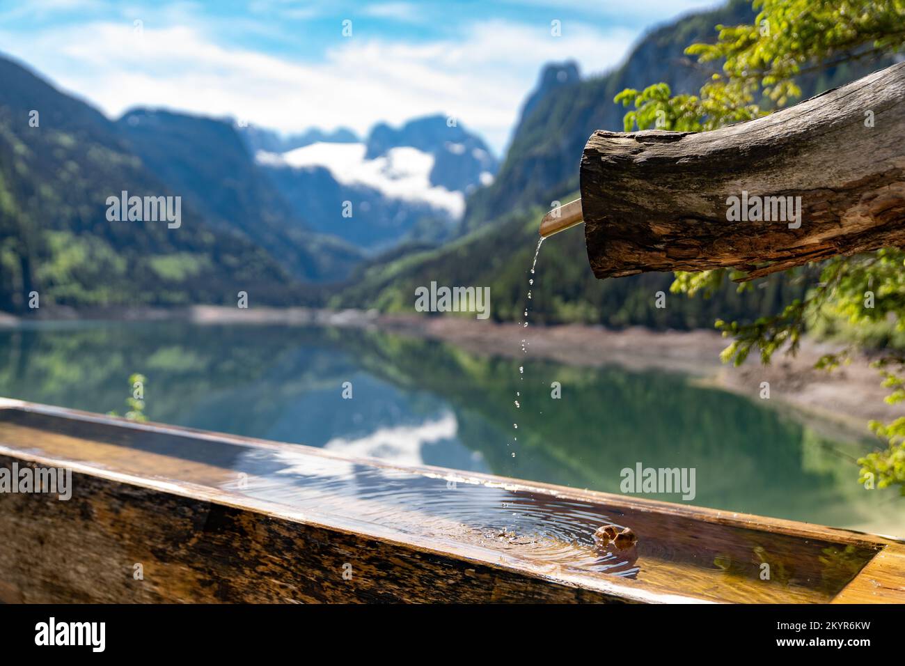 Alpine drinking water trough with Upper Austrian lake and mountains ...