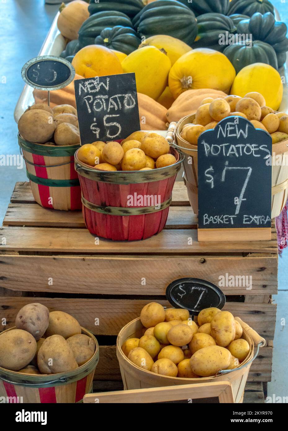 Market display of new potatoes in colorful baskets with chalk board ...