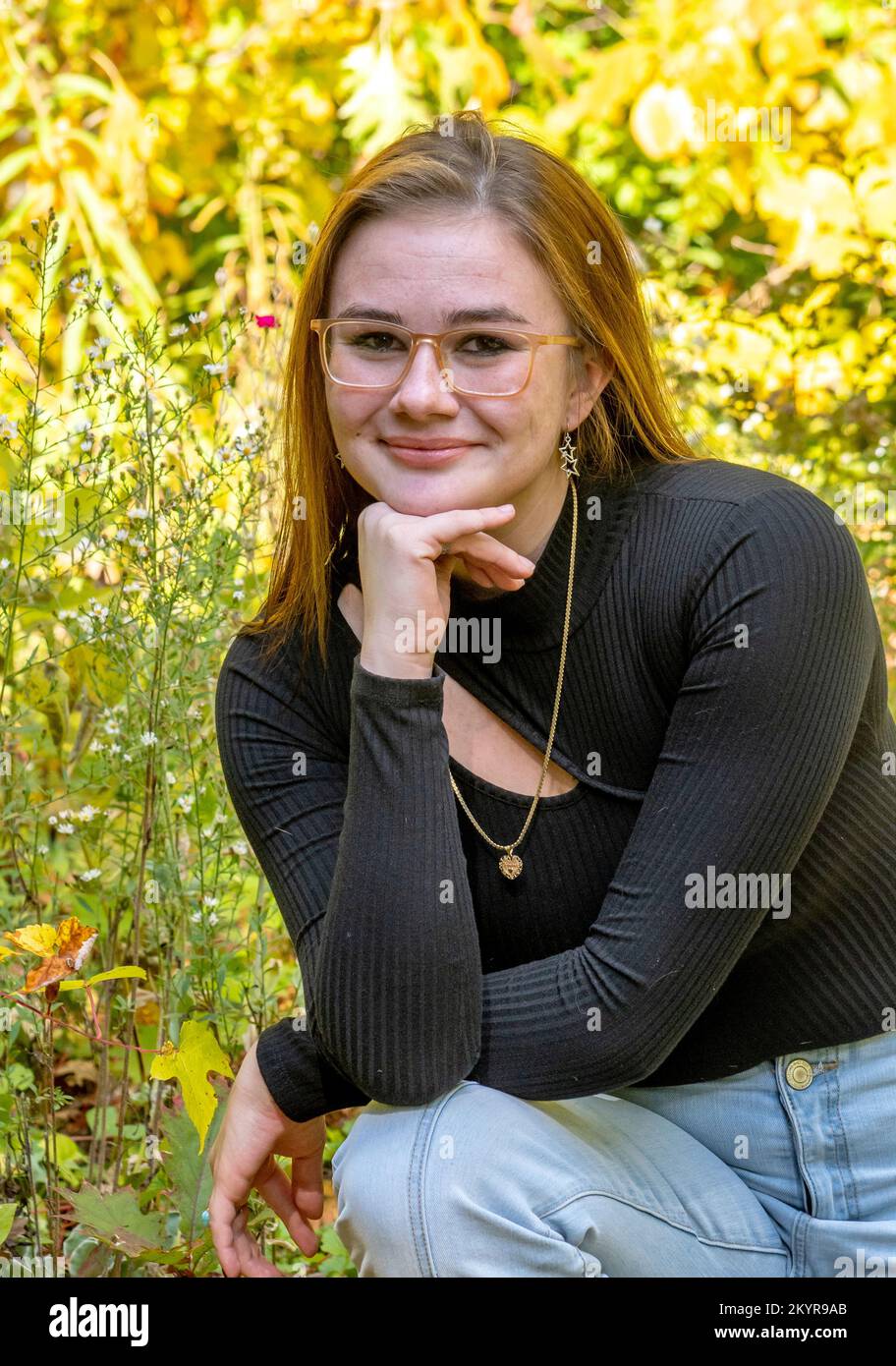 Pretty young lady sits outdoor in a golden and green field, and poses ...
