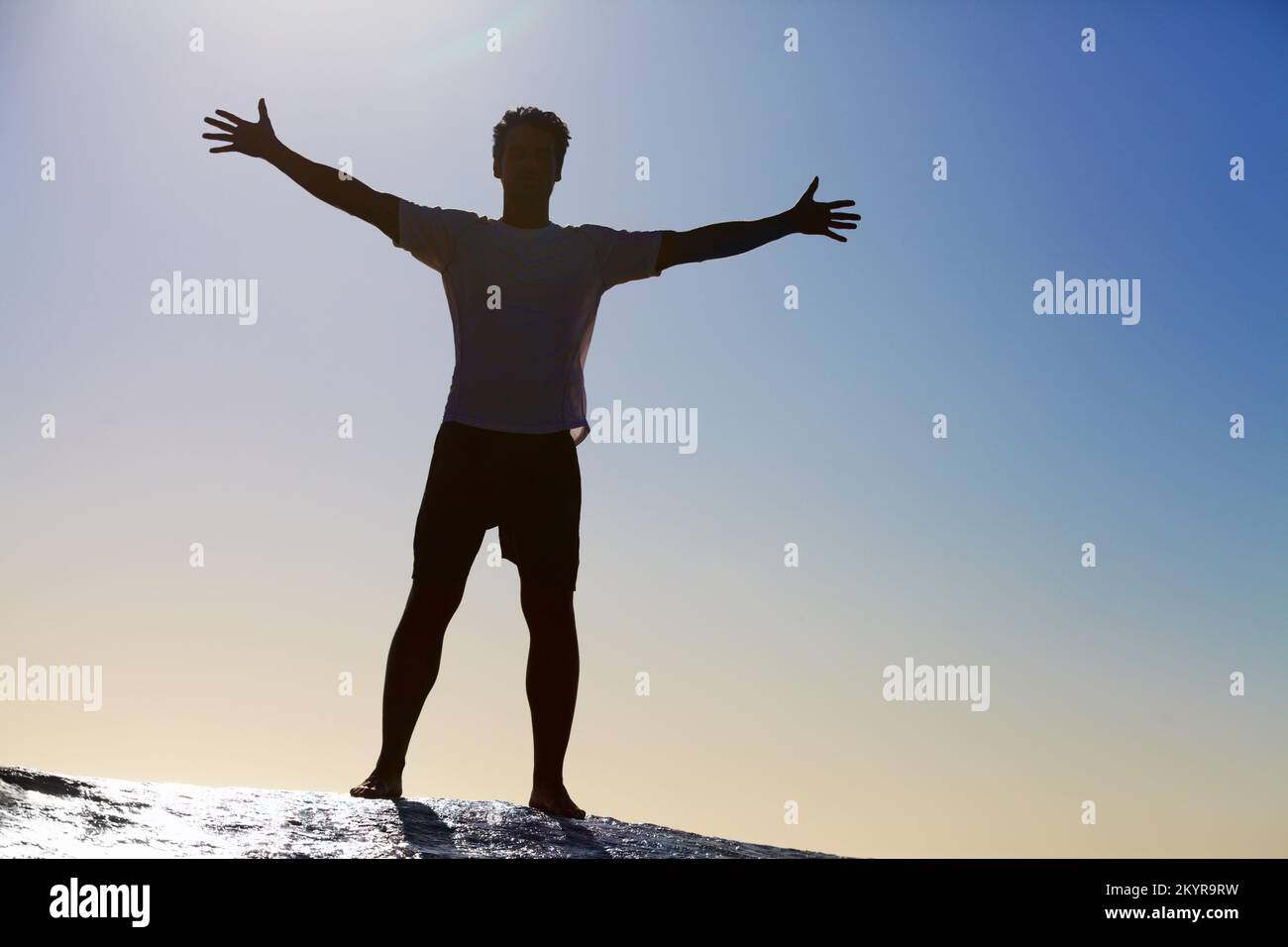 Mountain top freedom. Silhouette shot of a young man standing against ...