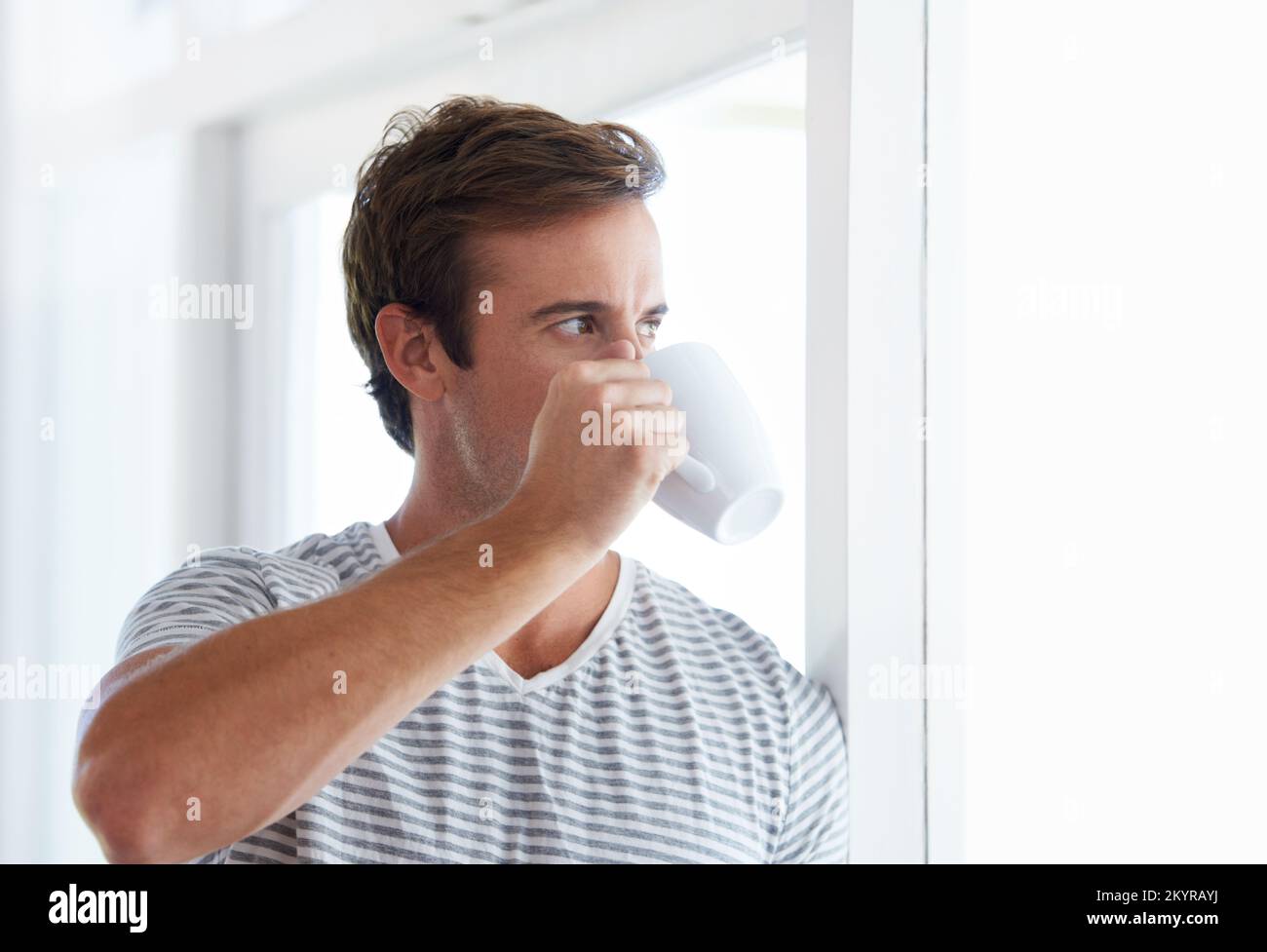 Sipping on a strong brew. A young man drinking a cup of coffee Stock ...