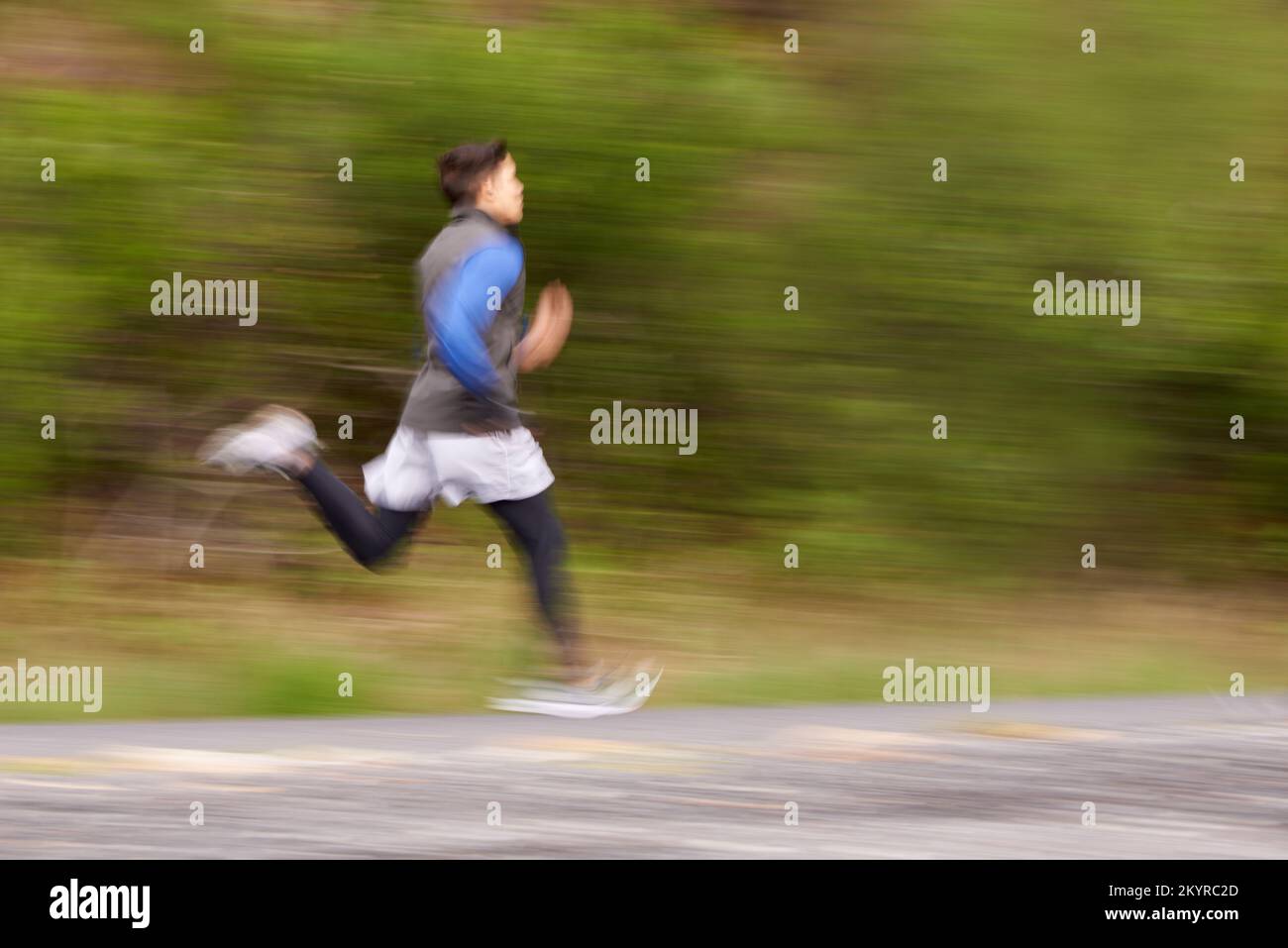 Burning up the road. Blurred image of a young man running along the ...